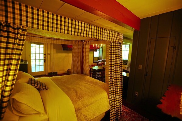 Quarto com cama grande, cortinas xadrez, mesa de jantar e guarda-roupa.