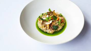 Um prato branco com molho verde, uma porção de comida no centro e guarnições.