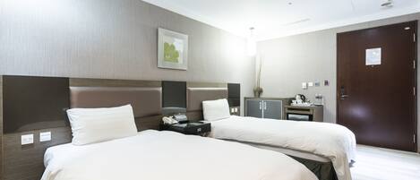 Quarto de hotel com duas camas, uma escrivaninha, um guarda-roupa e um espelho.