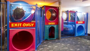 Uma área de recreação infantil com duas estruturas de jogo, uma identificada como “SAÍDA SOMENTE” e outra como “ENTRADA”.