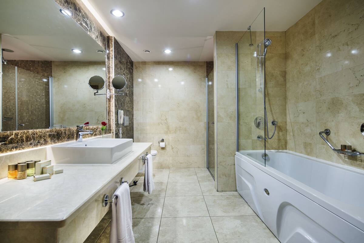 Uma casa de banho moderna com duas bacias, uma banheira, um chuveiro com divisória de vidro e um espelho grande.