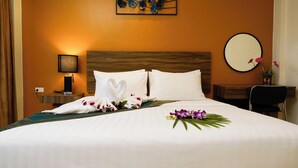 Uma cama bem arrumada com lençóis brancos, cabeceira de madeira e um buquê de flores sobre a cama.