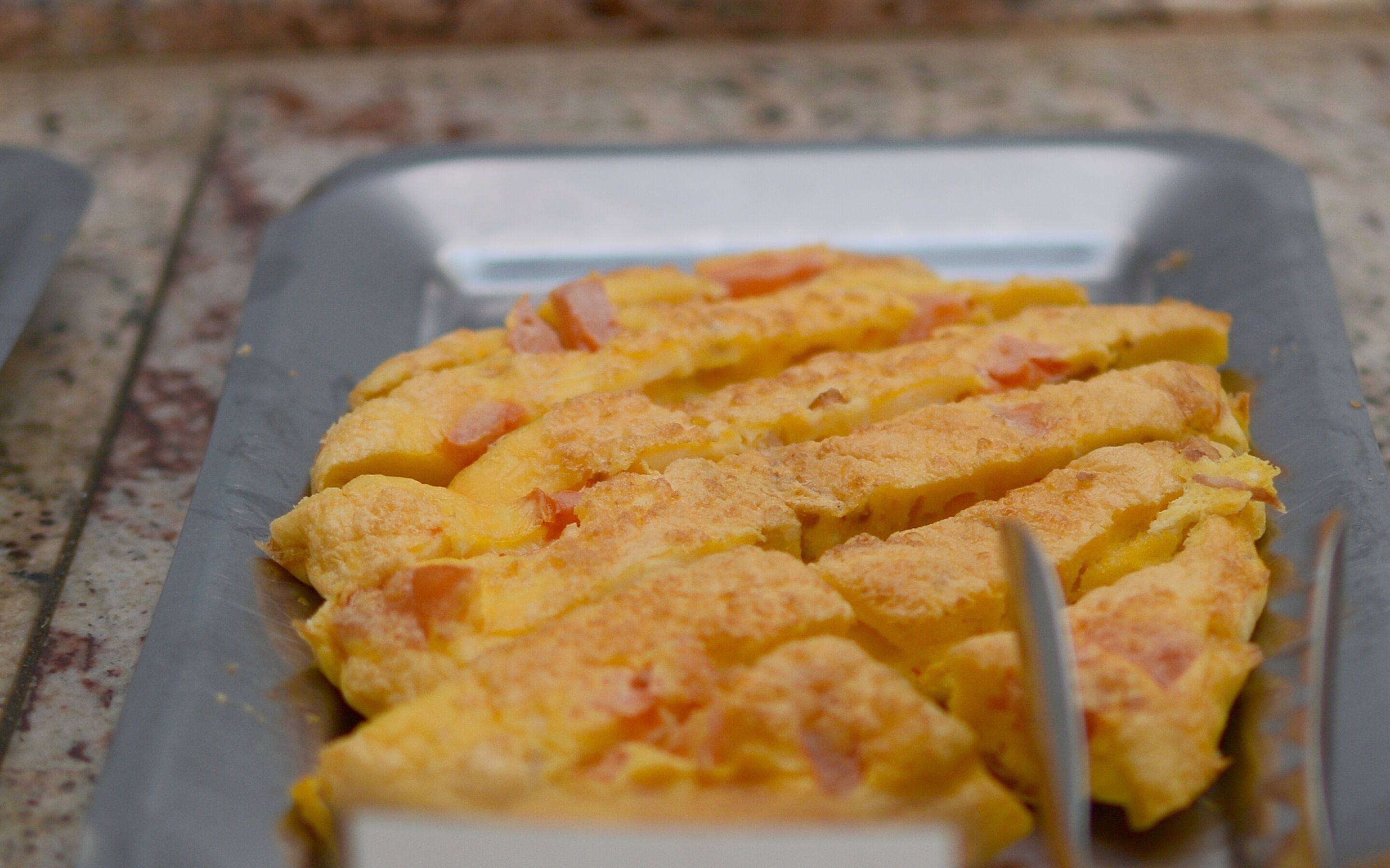 Uma bandeja com diversos alimentos, possivelmente um prato de café da manhã, sobre uma superfície metálica.