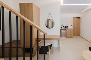 Interior moderno com escada de madeira, sala de jantar com mesa e cadeiras, e cozinha equipada.
