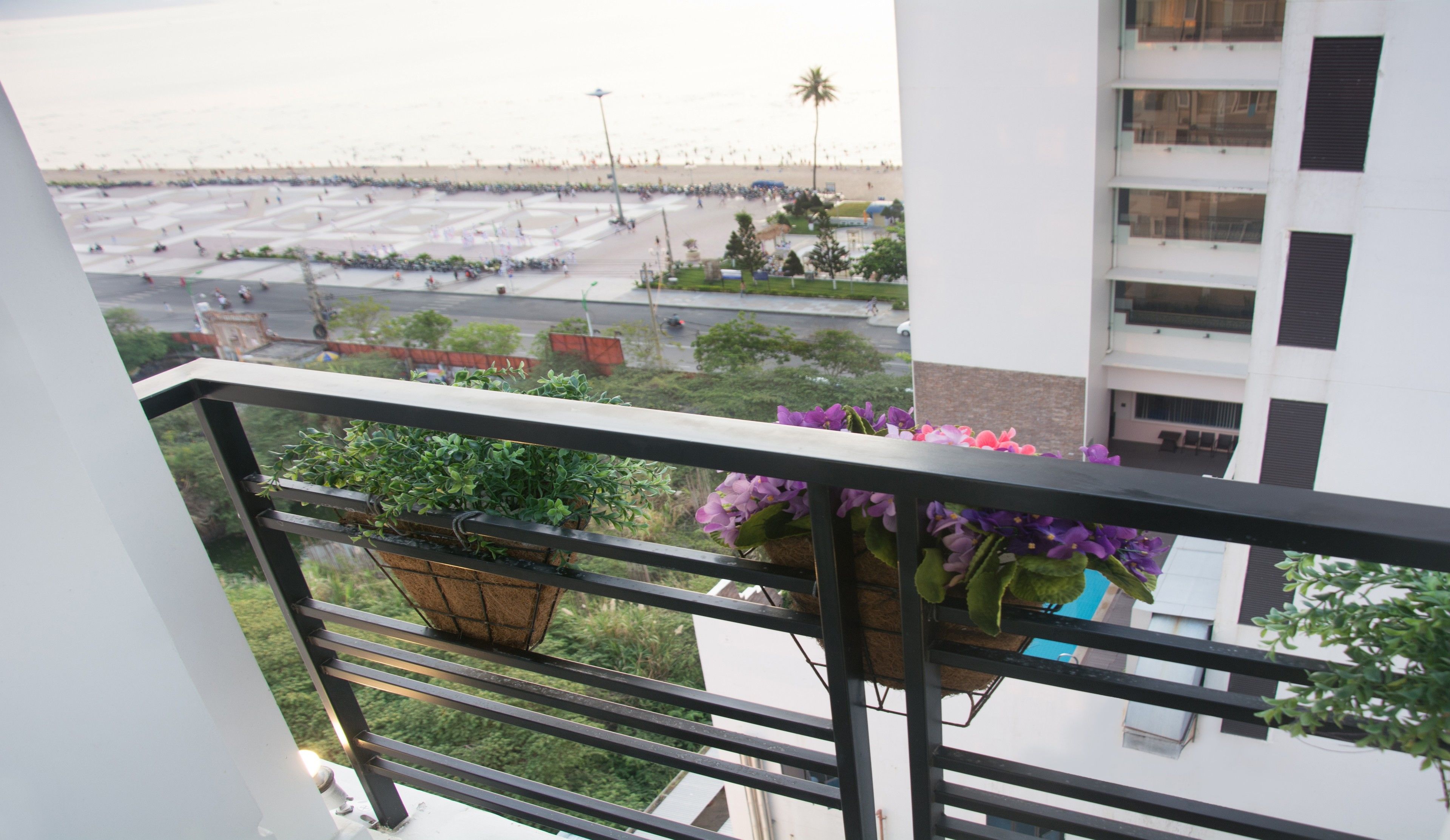 Varanda com plantas em vasos e vista para a praia e paisagem urbana.