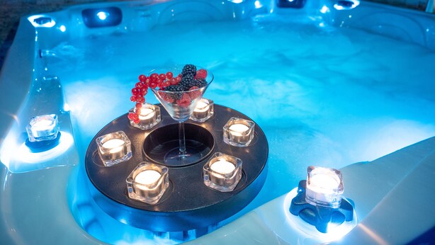 Uma banheira de hidromassagem com plataforma central e velas.