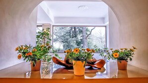 Um interior moderno com uma grande janela arqueada, superfície refletora e plantas em vasos.