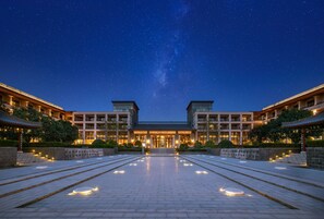 Um hotel com fachada simétrica, entrada central e um céu noturno estrelado.