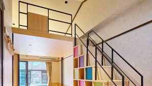 Um interior moderno com um quarto no mezanino, uma escada com espaço para armazenamento colorido e vista para o exterior.