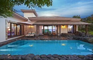 Uma casa moderna com piscina, varanda coberta e vista para o oceano.
