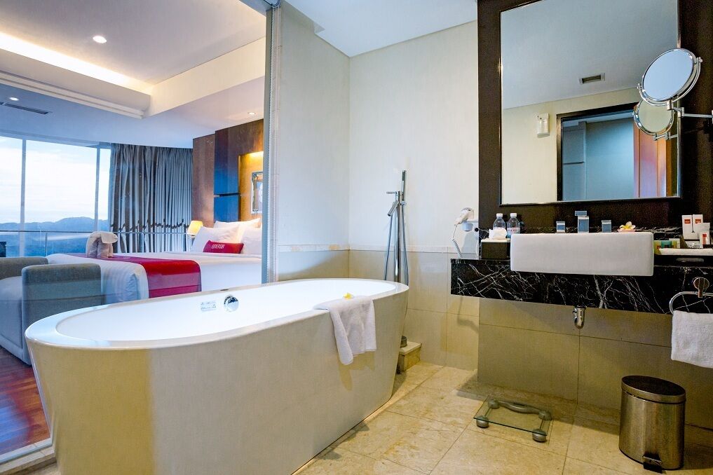 Casa de banho de hotel moderna com uma banheira grande, chuveiro e toucador com espelho.
