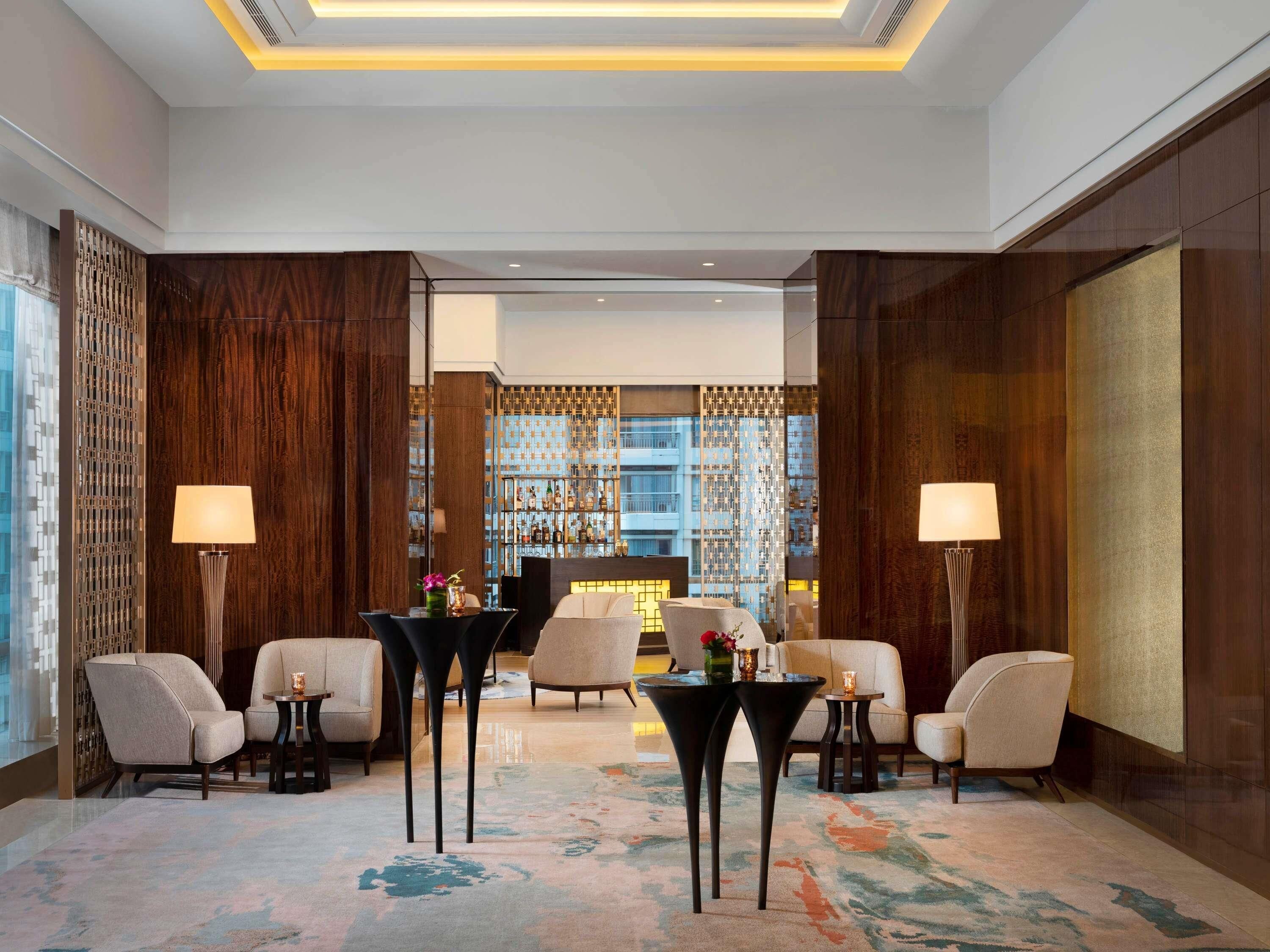 Um lobby moderno com área de bar, espaços para sentar e uma parede decorativa.