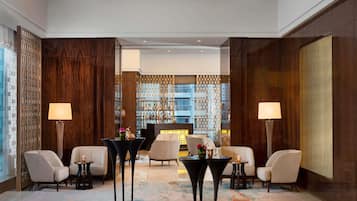 Um lobby moderno com área de bar, espaços para sentar e uma parede decorativa.