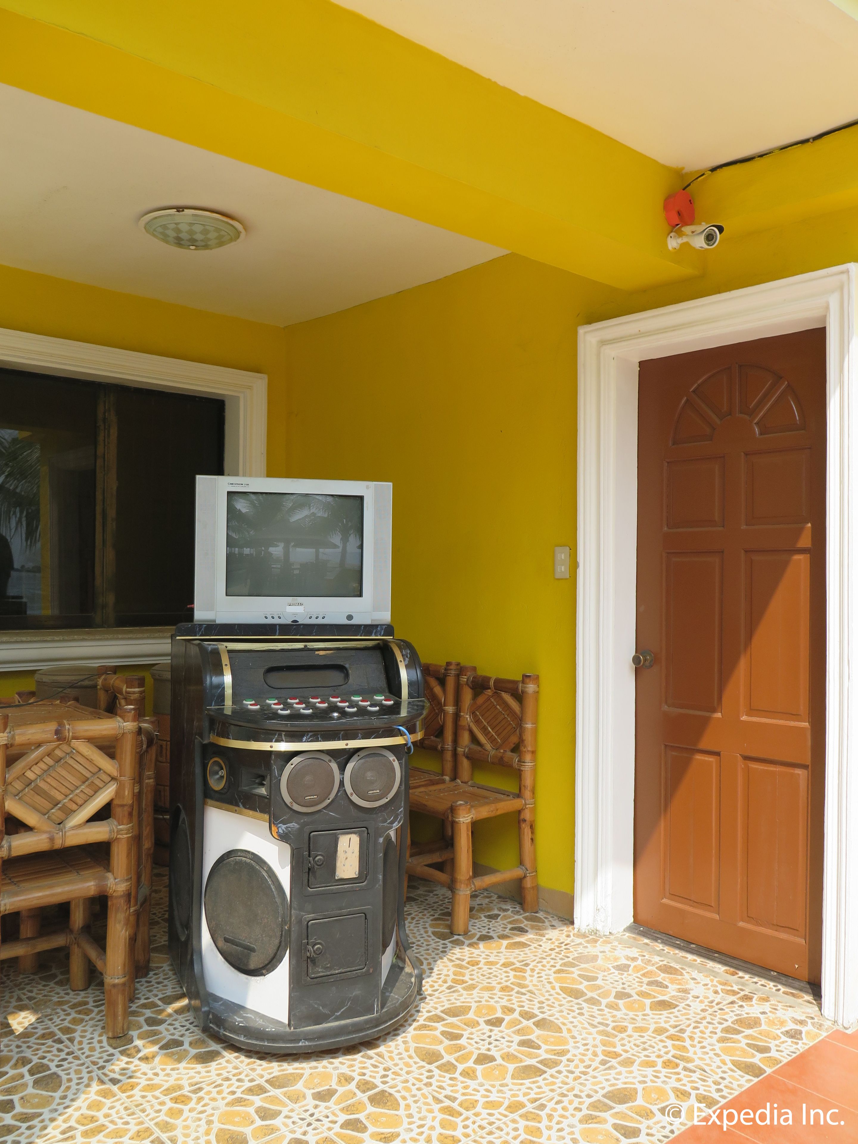Um quarto com televisão sobre um suporte, uma porta e uma janela com persianas.