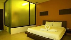 Quarto de hotel com uma cama grande, um espelho e uma televisão presa à parede.