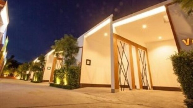 Entrada de um hotel moderno com fachada bem iluminada, área externa coberta e caminho acessível à entrada.