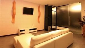 Uma sala de estar moderna com um sofá, uma TV de tela plana na parede e um armário com portas deslizantes.