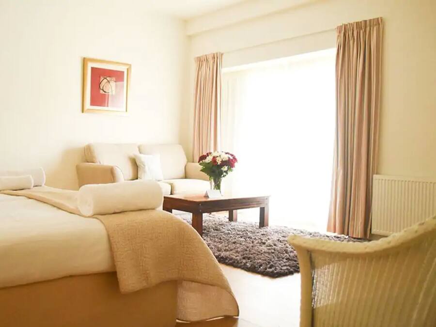 Quarto de hotel com uma cama grande, um sofá, uma mesa pequena e uma cadeira.