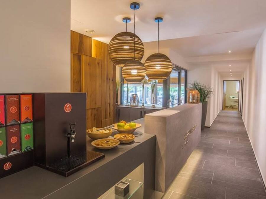 Área de recepção de hotel com estação de café, exposição de caixas de chá e design de interiores moderno.