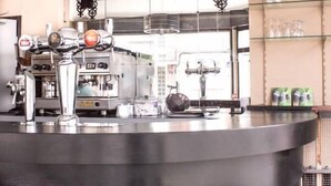 Uma cozinha industrial com eletrodomésticos de aço inoxidável, uma máquina de café e uma pia de metal.