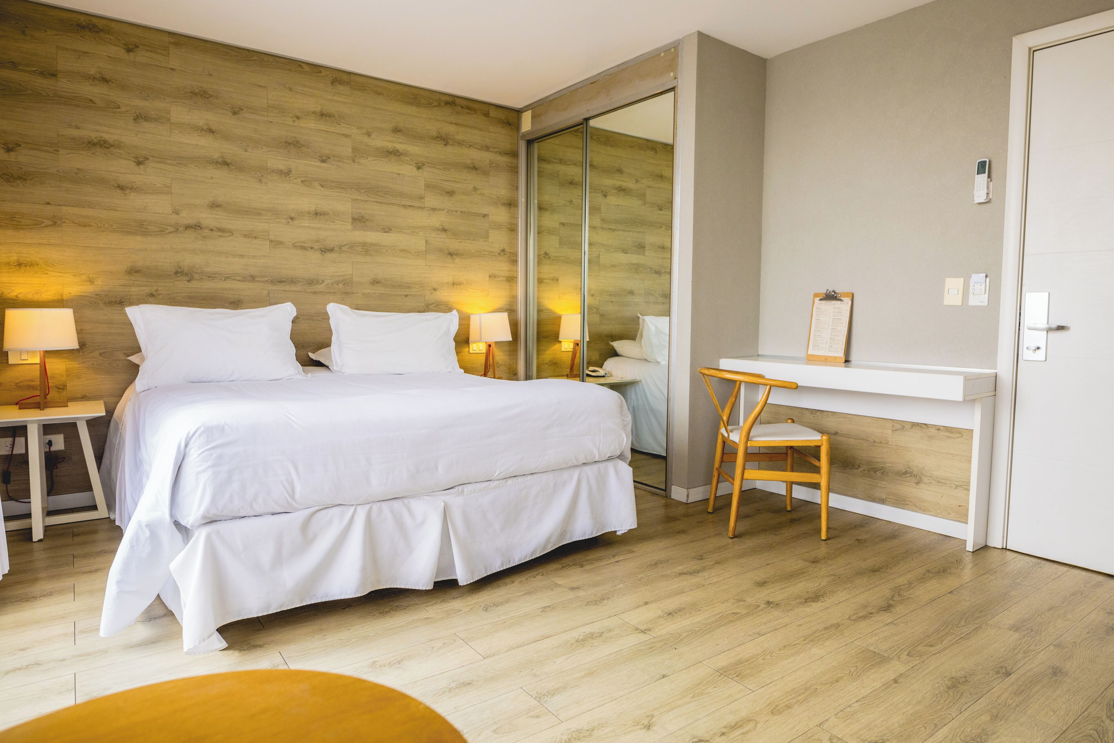 Quarto de hotel moderno com uma cama grande, uma escrivaninha e um espelho.