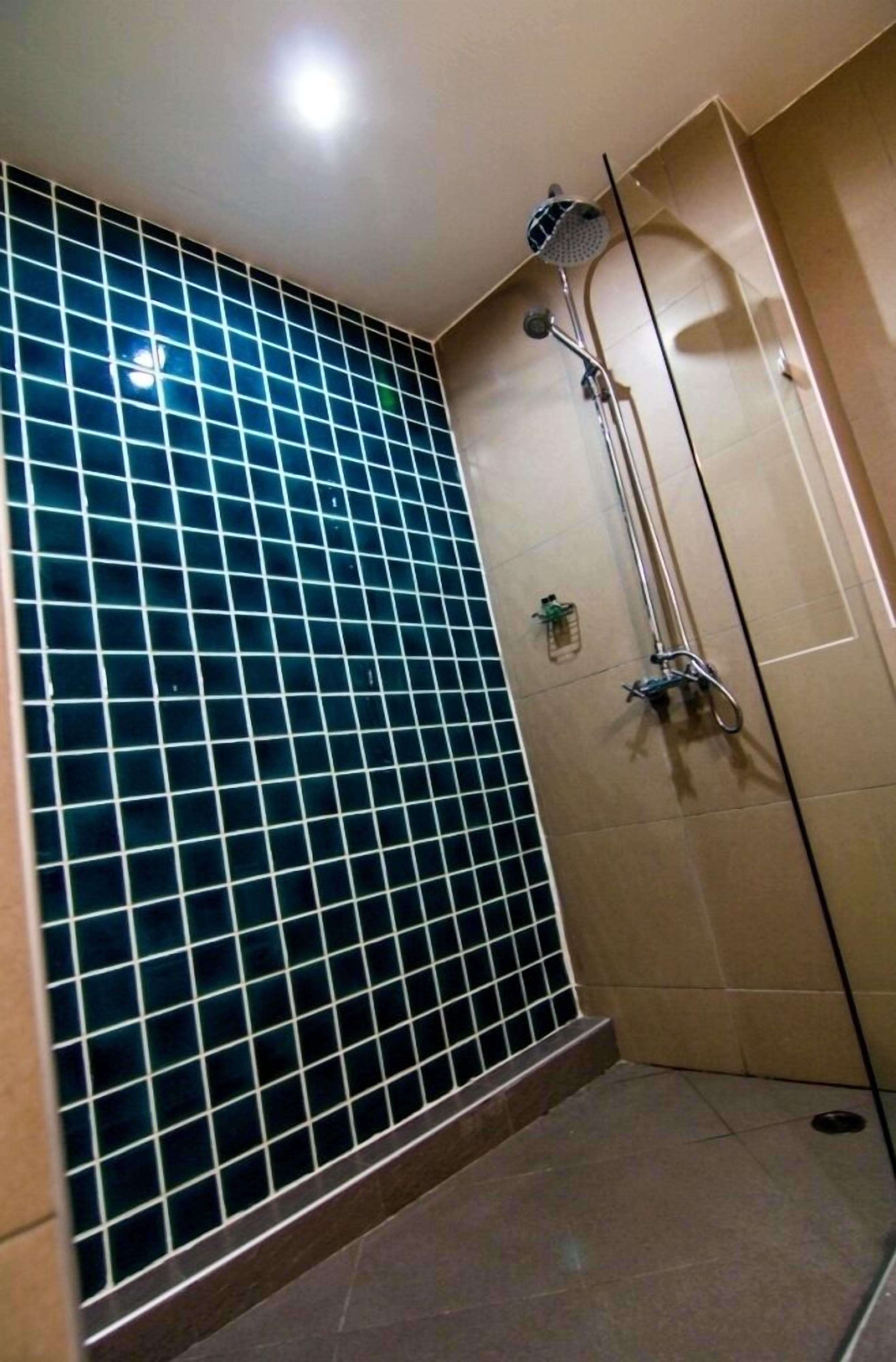 Área de chuveiro com parede revestida em azulejos e um chuveiro.