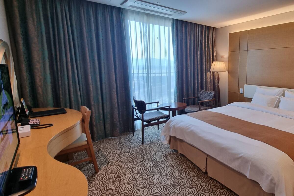 Quarto de hotel com uma cama grande, uma escrivaninha e uma cadeira.