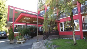 Um edifício vermelho com varanda e um letreiro com a inscrição 'Sporthotel'.