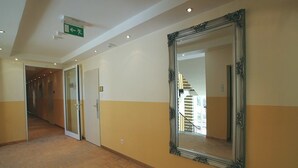 Um corredor com um espelho grande, uma escada e uma placa de saída.