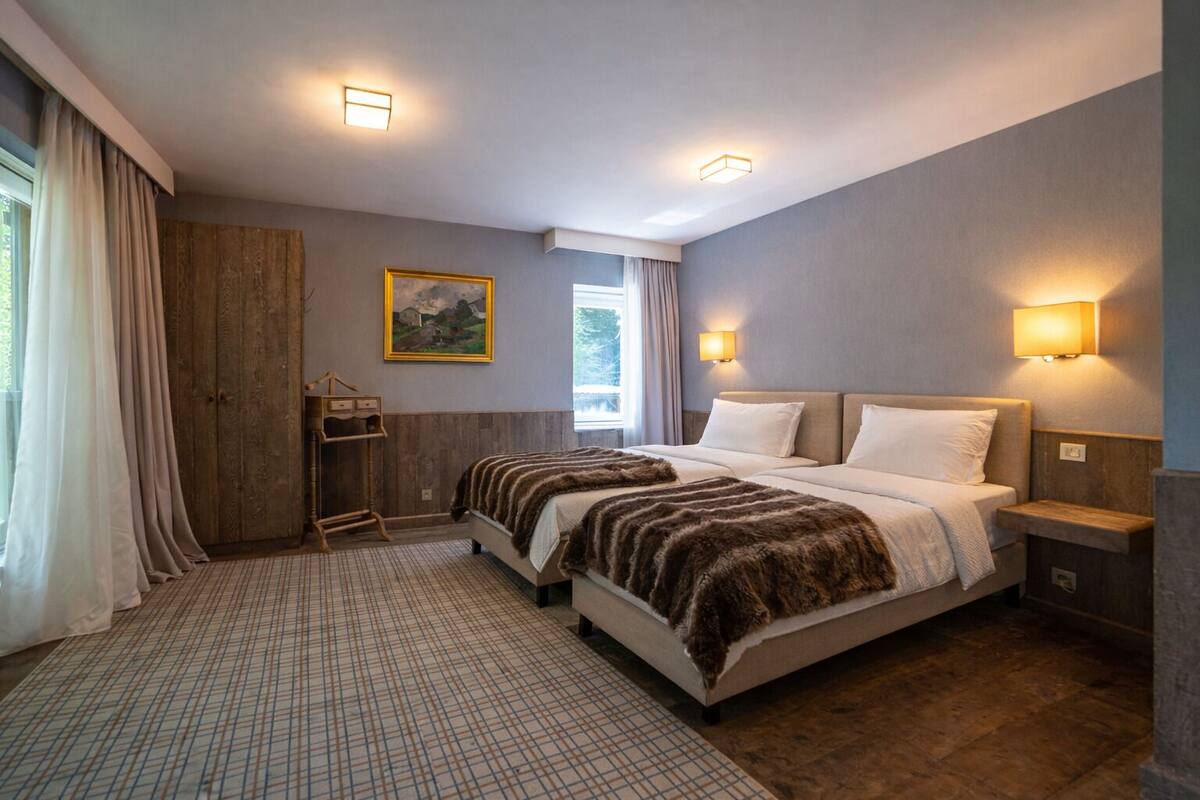 Quarto de hotel com duas camas, guarda-roupa de madeira, um quadro e luminárias na parede.