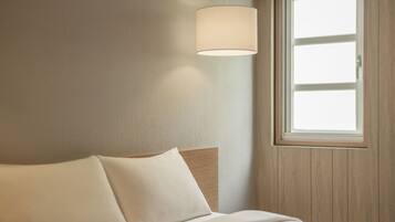Quarto de hotel com cama, janela e luminária na parede.
