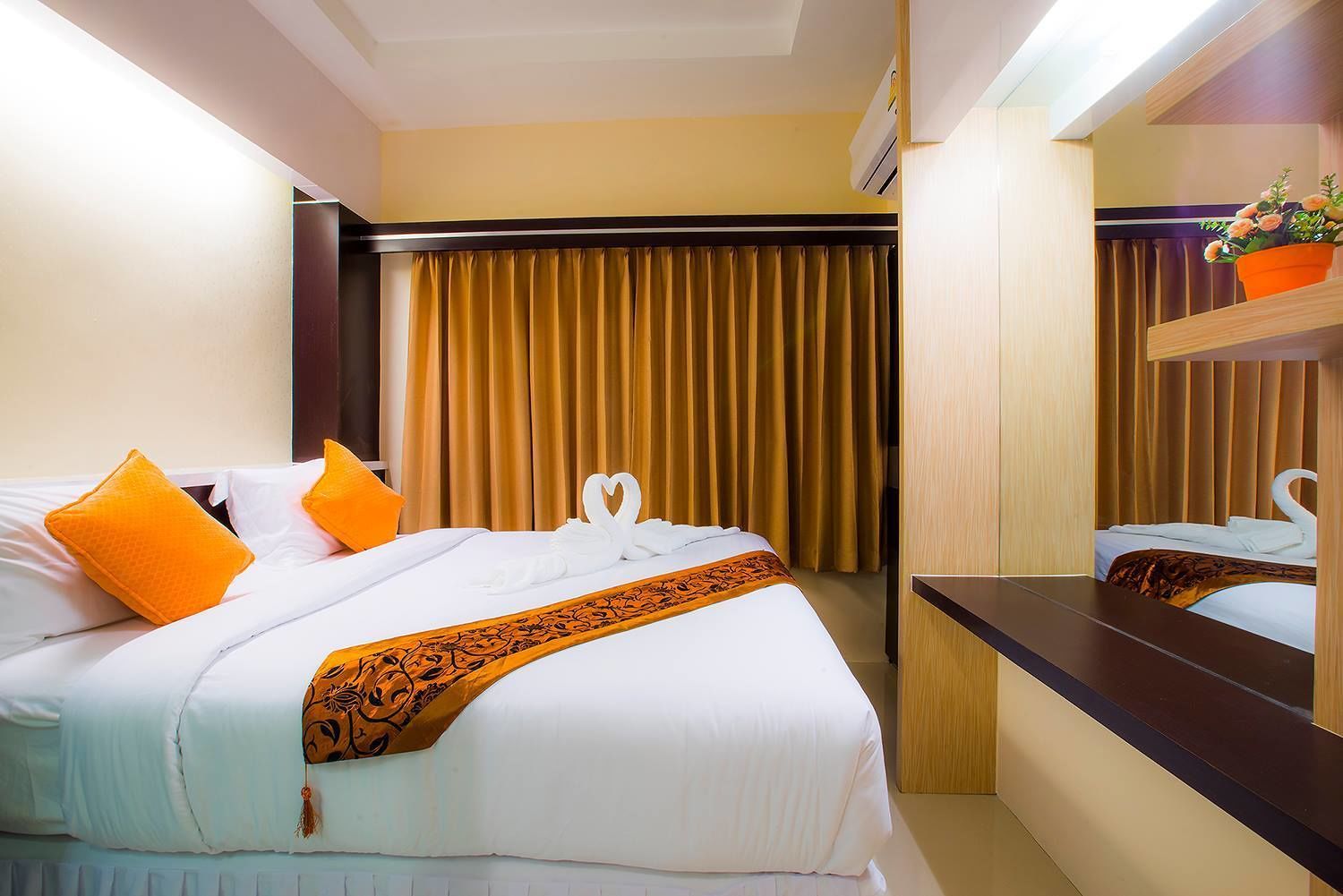 Quarto de hotel com cama, mesa de cabeceira, espelho e janela com cortinas.