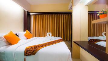 Quarto de hotel com cama, mesa de cabeceira, espelho e janela com cortinas.