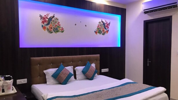 Quarto de hotel moderno com uma cama grande, uma obra de arte na parede e um lustre.