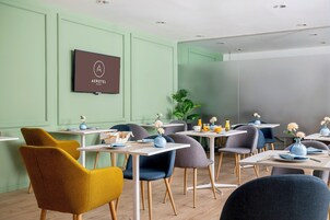 Uma sala de jantar moderna com mesas, cadeiras e um logotipo na parede.