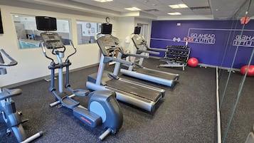 Academia com esteiras, elípticos e máquinas de musculação.