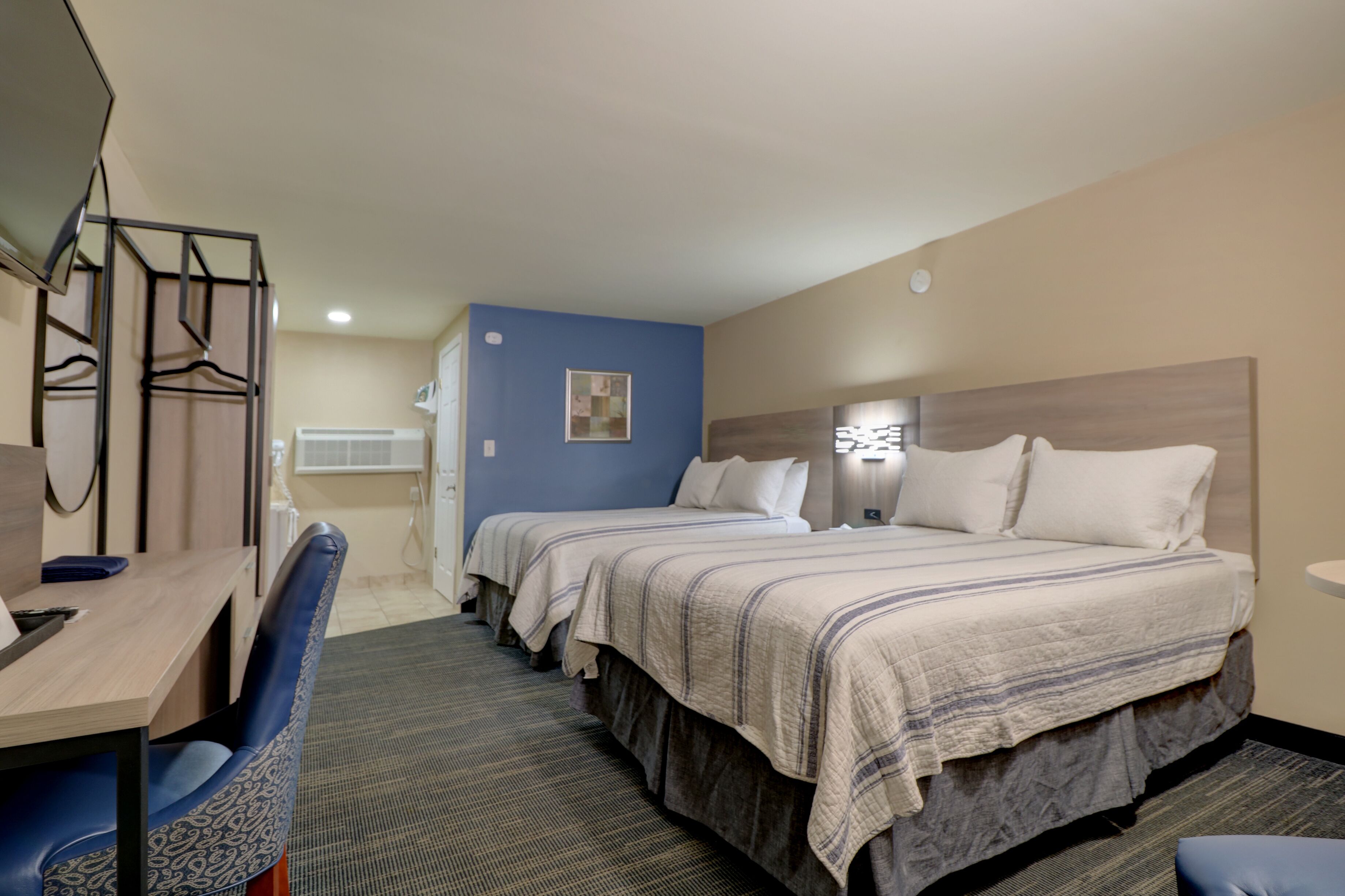 Quarto de hotel com duas camas, uma escrivaninha e uma cadeira.