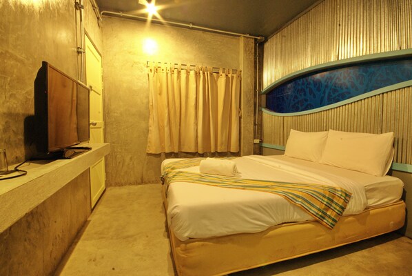 Quarto de hotel com cama, televisão sobre suporte, janela com cortinas e parede com painel decorativo.