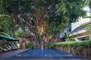 Área de piscina com espreguiçadeiras e um cenário com árvores.