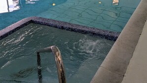 Piscina interna com água cristalina, um flutuador e um mural na parede.