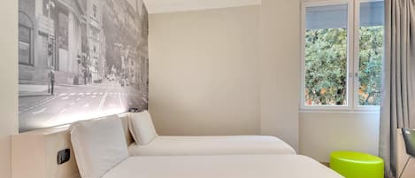 Quarto moderno com cama, um banquinho verde, janela com vista para árvores e interruptor de luz na parede.