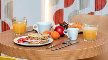 Uma mesa de café da manhã com torradas, frutas, croissants e suco de laranja.