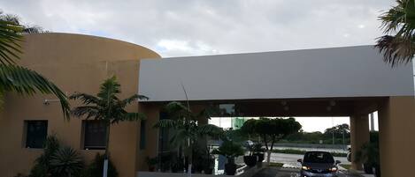 Um edifício moderno com fachada curva, entrada coberta e calçada pavimentada.