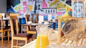 Disposição para o café da manhã com um jarro de suco de laranja, cereais e uma cesta de frutas em um serviço de bandeja.