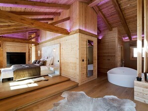 Interior de cabana de toras com uma cama, banheiro e uma janela grande.