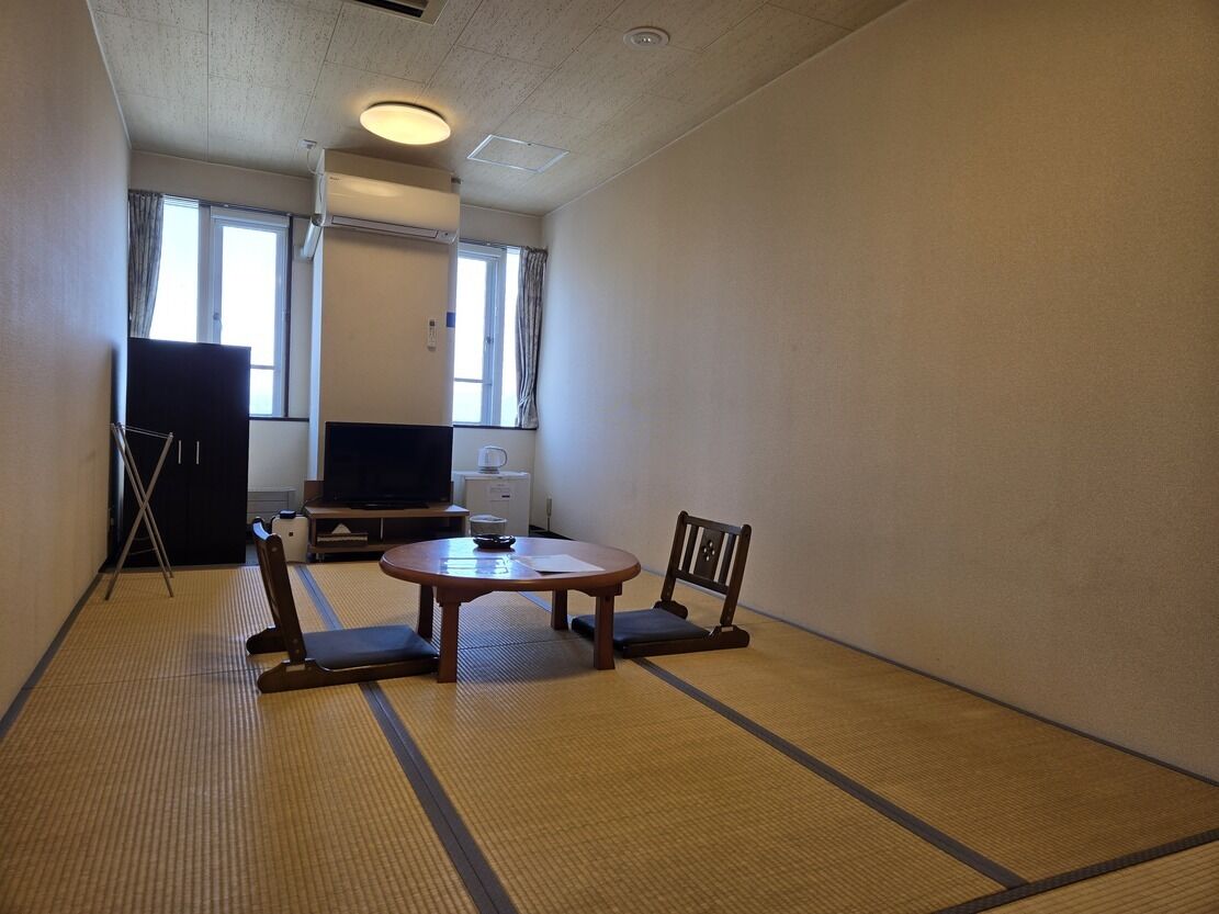 Quarto com tatames, televisão, escrivaninha e cadeira.