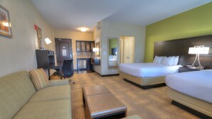 Quarto de hotel com sofá, cama, escrivaninha e espelho.