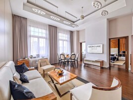 Quarto de hotel moderno com sofá, mesa de jantar e uma janela ampla.