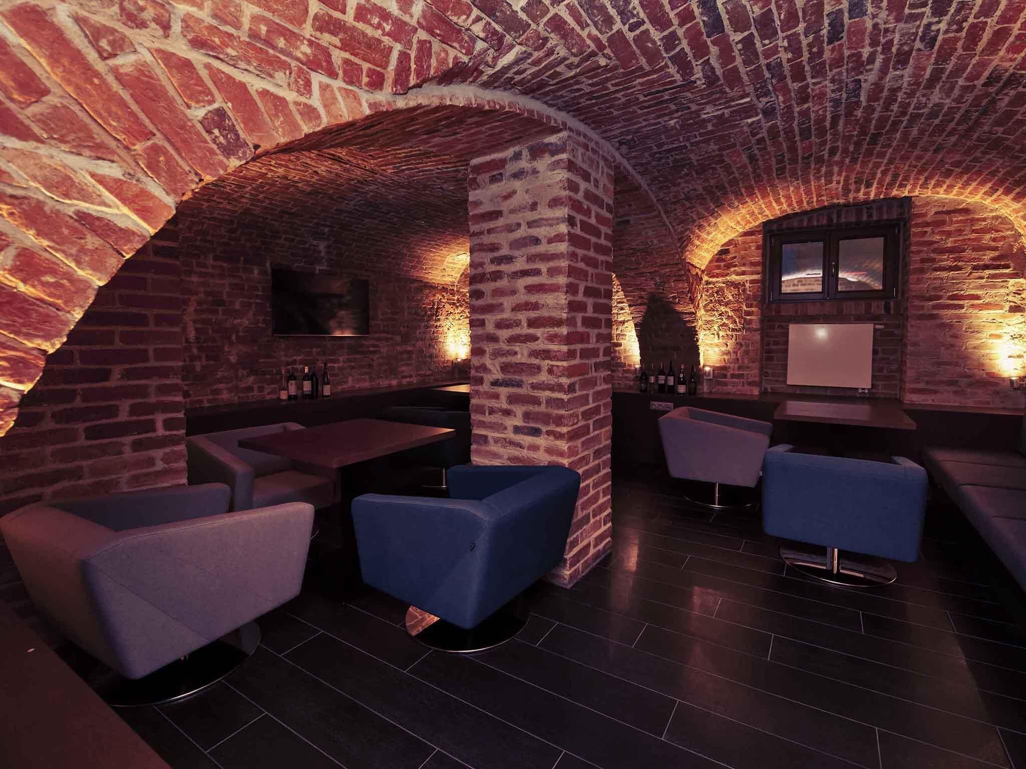 Uma área de bar com paredes de tijolo, assentos e uma tela de televisão.