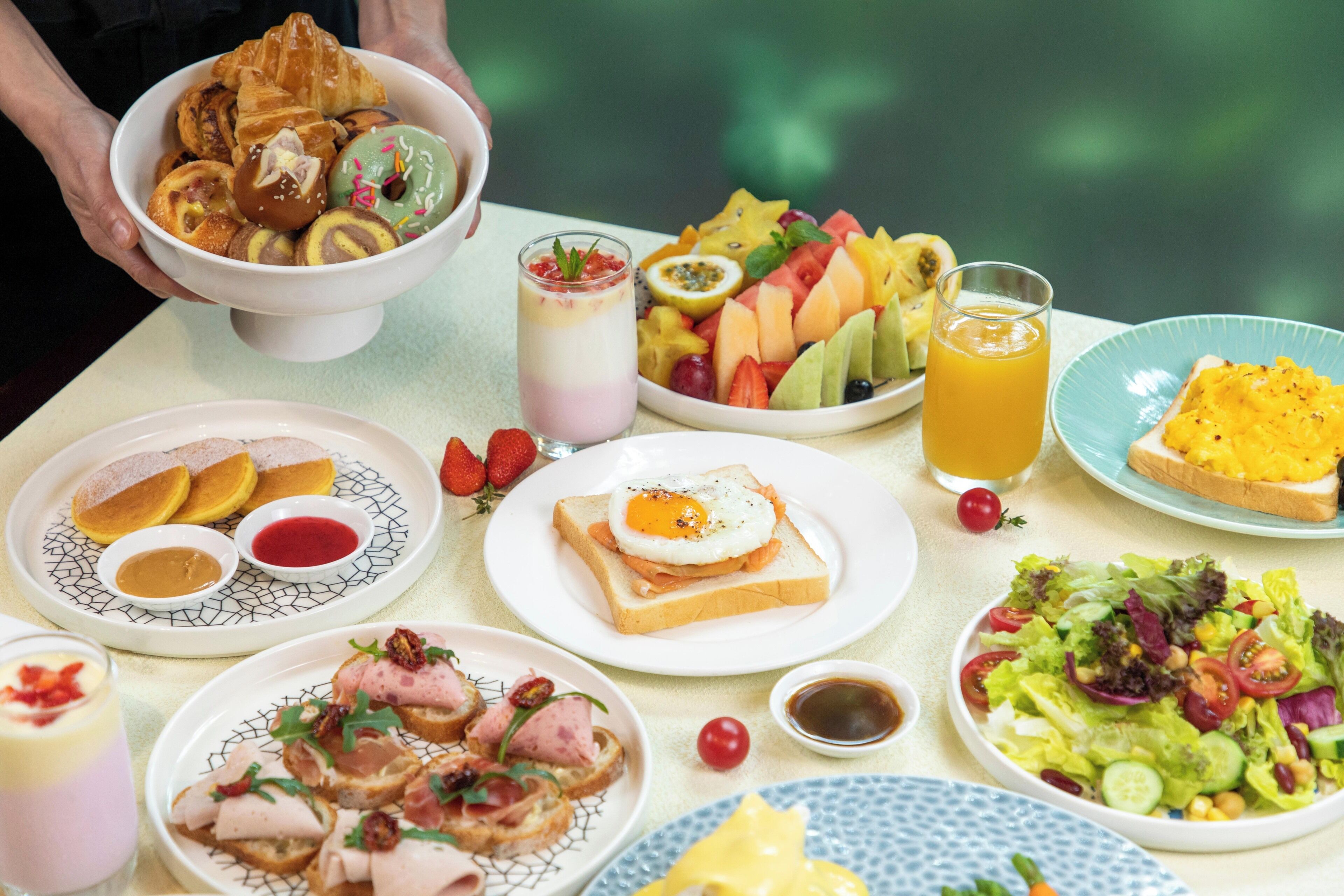 Diversos pratos de pequeno-almoço, incluindo panquecas, ovos e fruta.